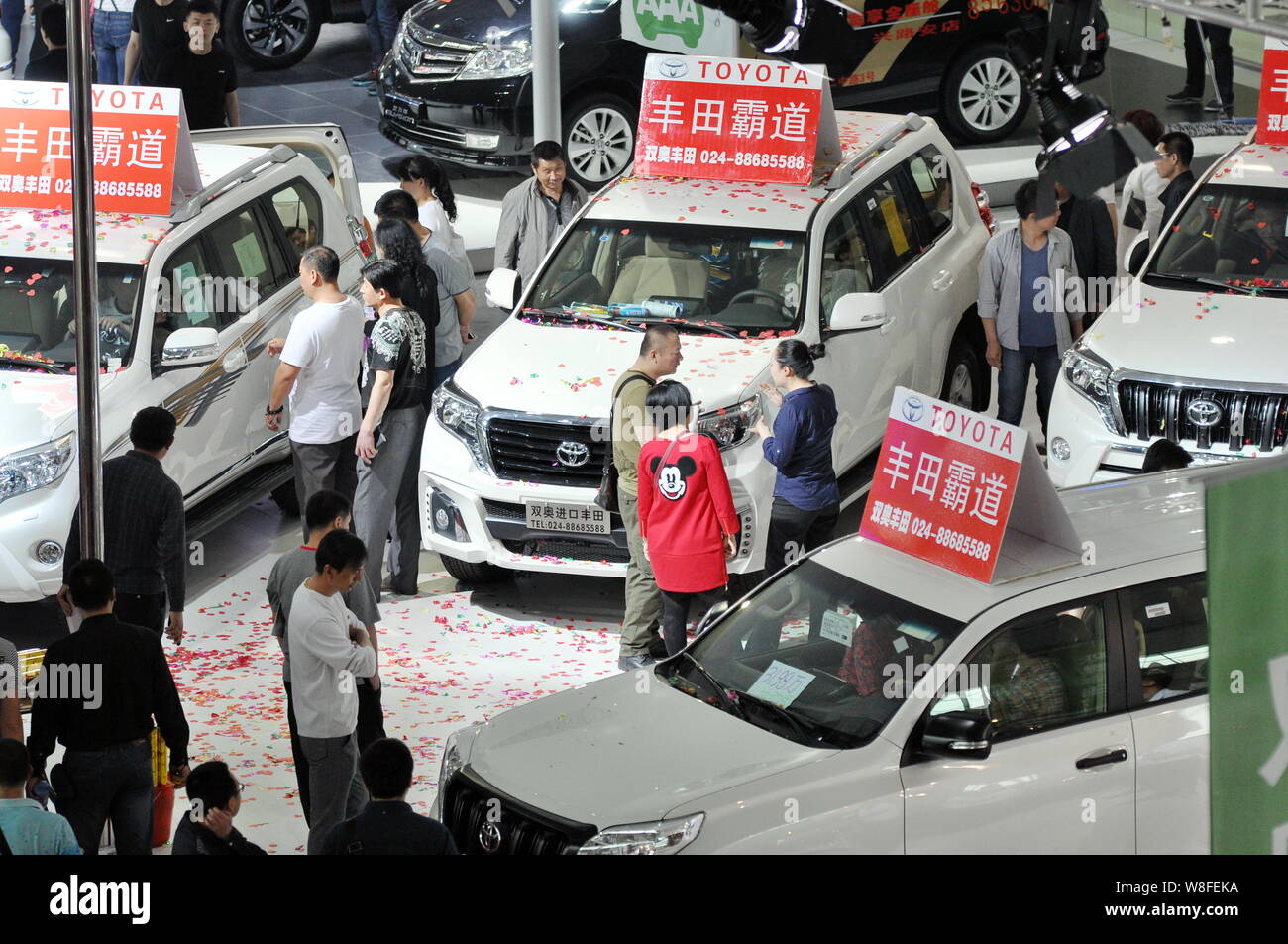 Visitors try out or look at Toyota cars on display during an auto show ...
