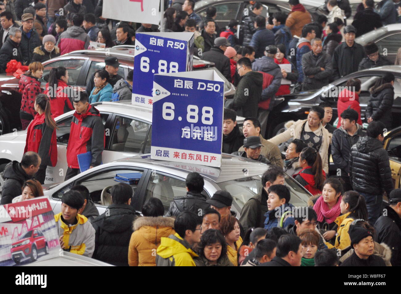 Visitors crowd around cars on display at an auto show in Shenyang city ...
