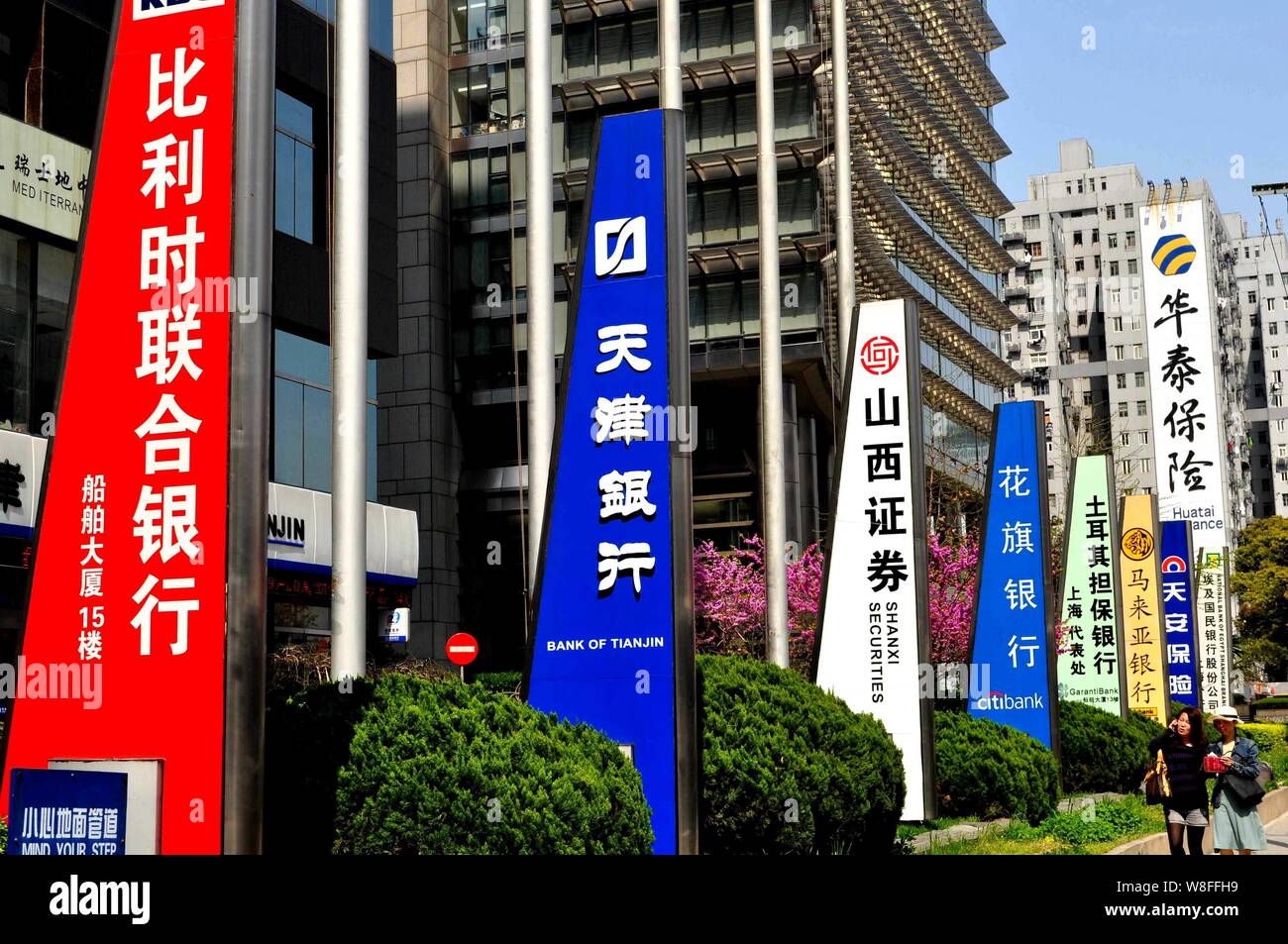 --FILE--Pedestrians walk past signboards of Chinese and foreign ... --FILE--Pedestrians walk past signboards of Chinese and foreign ...