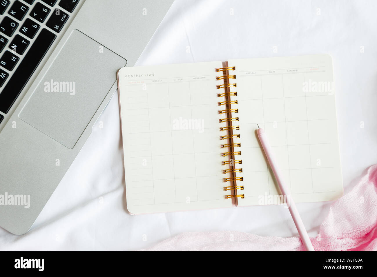 Flat lay bed workspace with laptop, planner, pen on white background ...