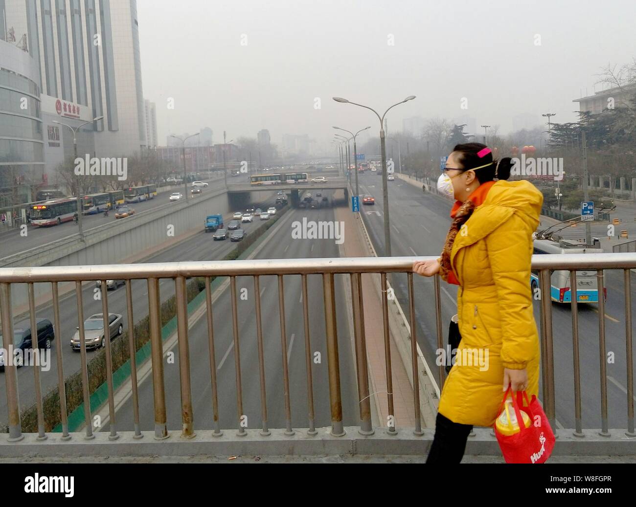 A pedestrian wearing a face mask walks through a footbridge in heavy ...