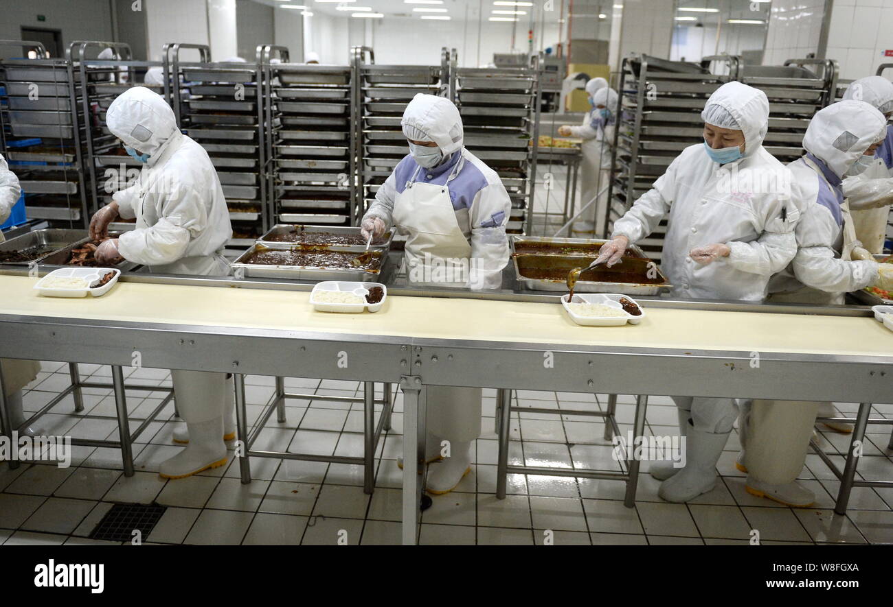 Chinese workers fill lunch boxes with food on the production line at a ...