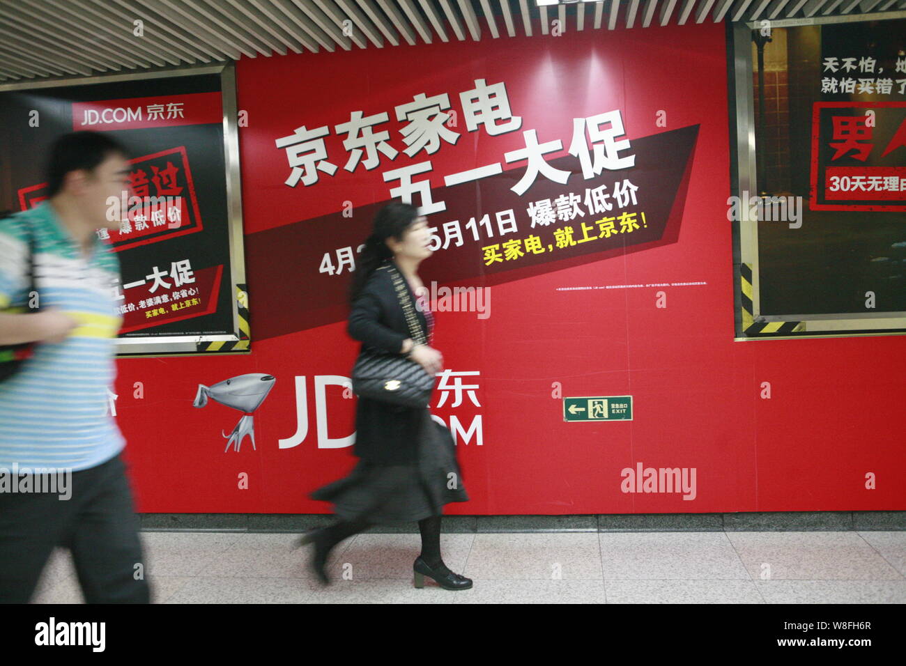 --FILE--Passengers walk past an advertisement for online shopping site ...