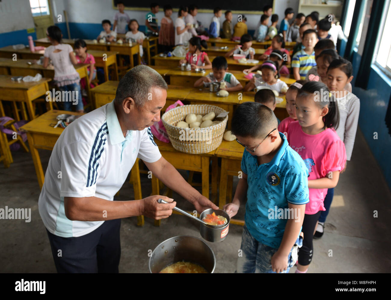--FILE--Students queue up to get their lunch in a classroom at a ...