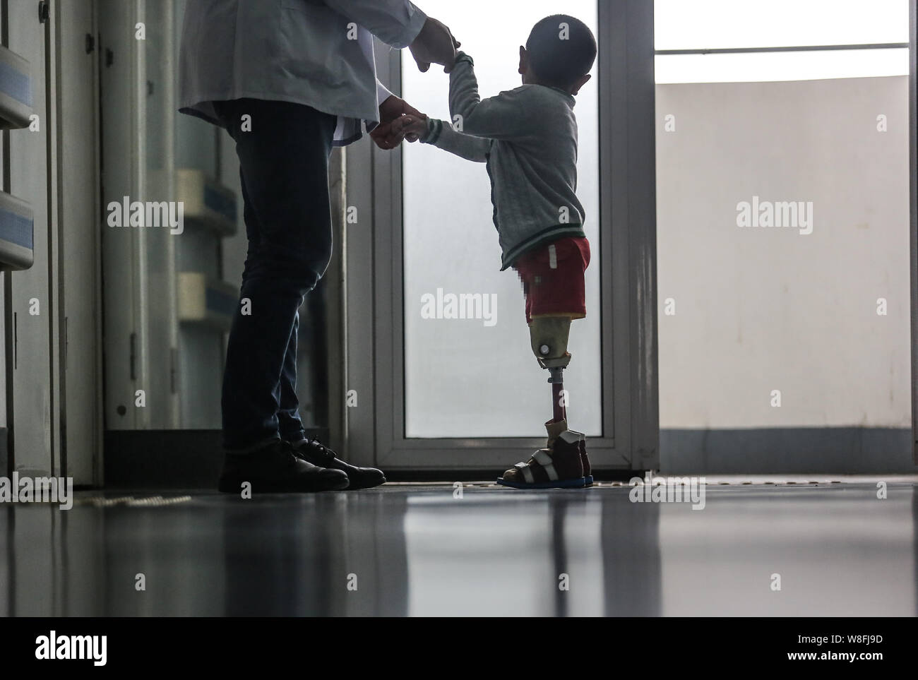 A physiotherapist holds hands of the four-year-old legless boy Xiao ...