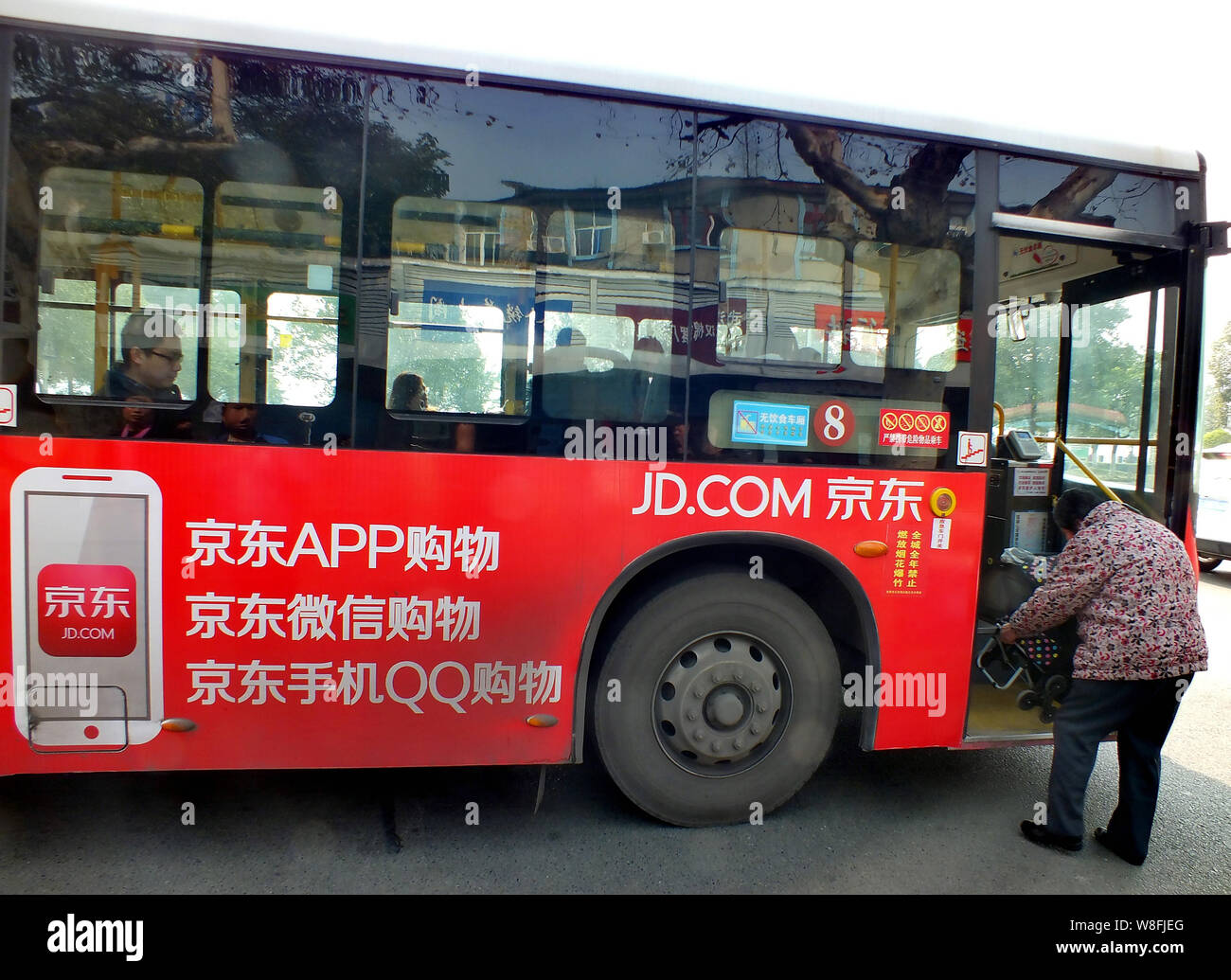 --FILE--An elderly woman gets on a bus with an advertisement for JD.com ...