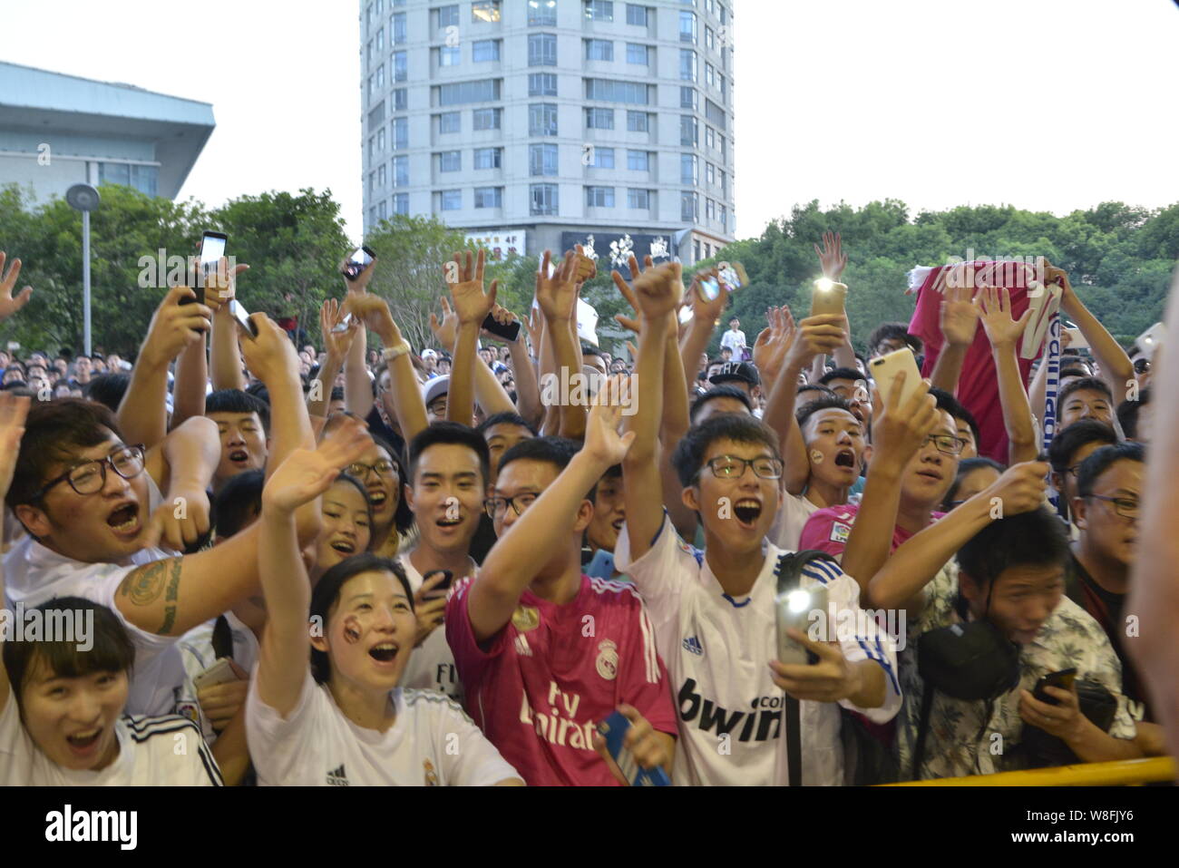 A crowd of football fans shout to greet players of Real Madrid and AC ...
