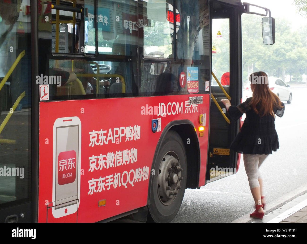 --FILE--A passenger gets on a bus with an advertisement for Chinese ...