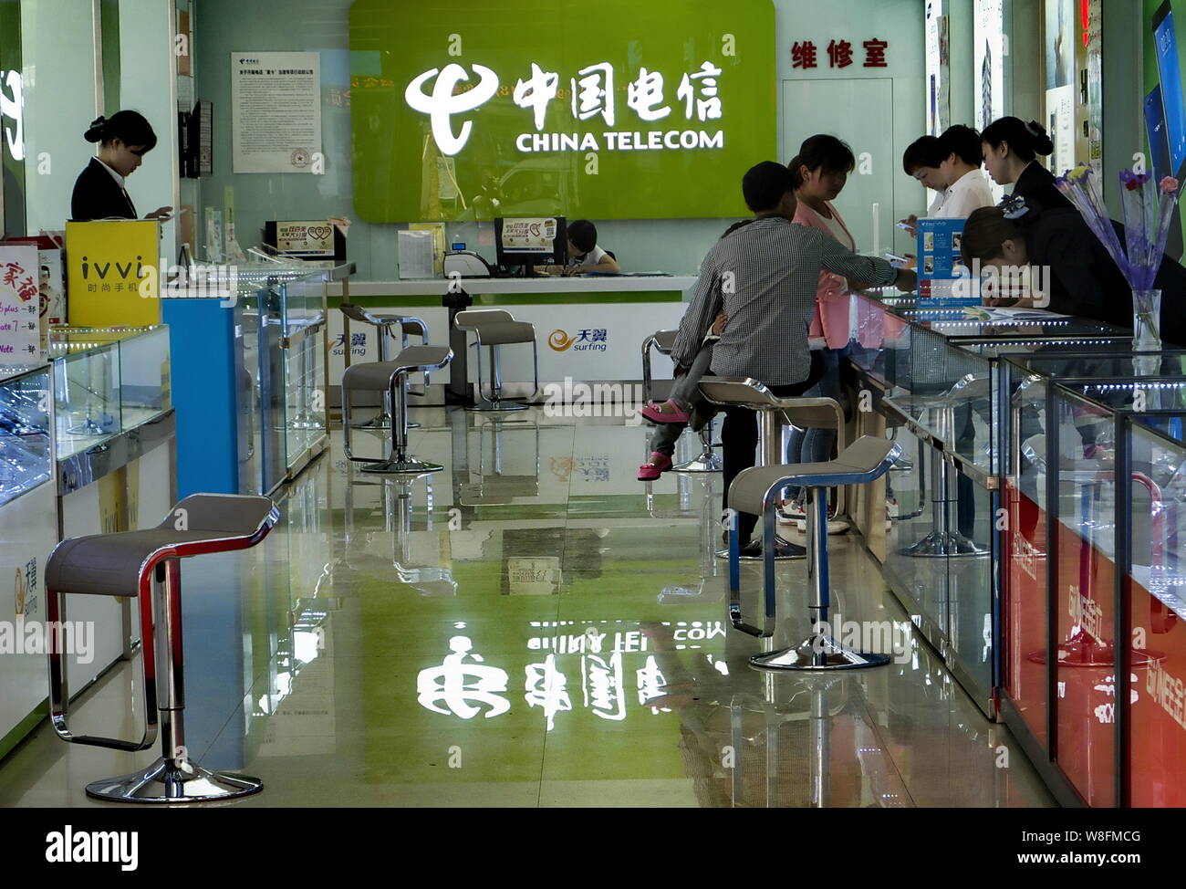 --FILE--Chinese employees serve customers at a branch of China Telecom ...