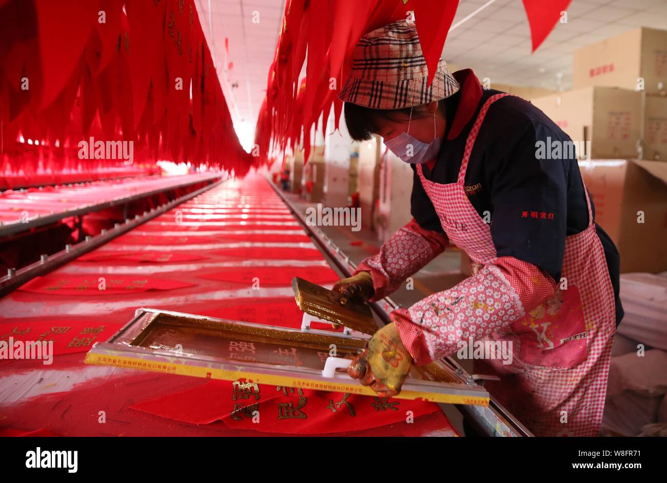 A Chinese worker imprints Chinese characters on fabrics used to make ...