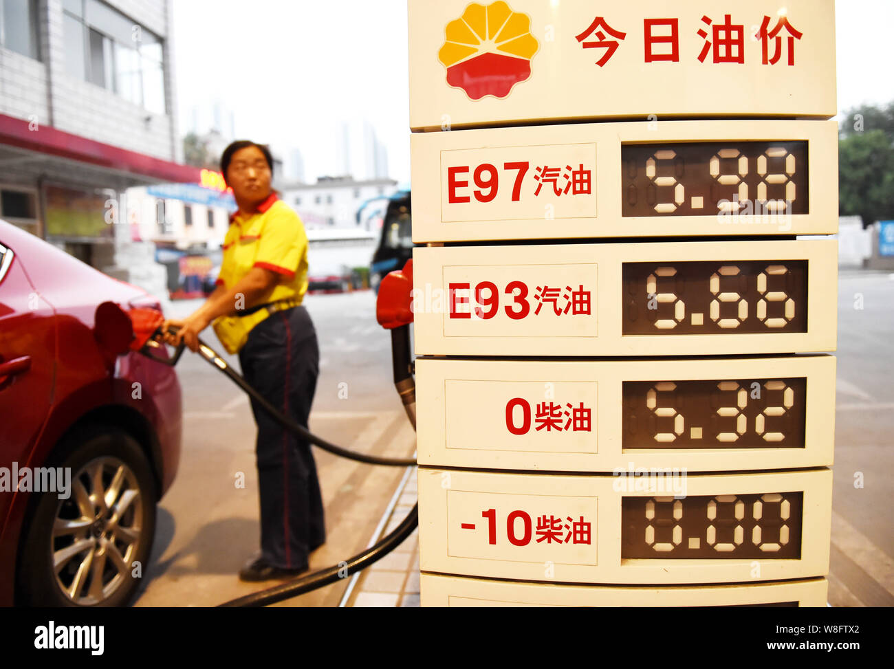 --FILE--A Chinese worker refuels a car next to a price board at a gas ...