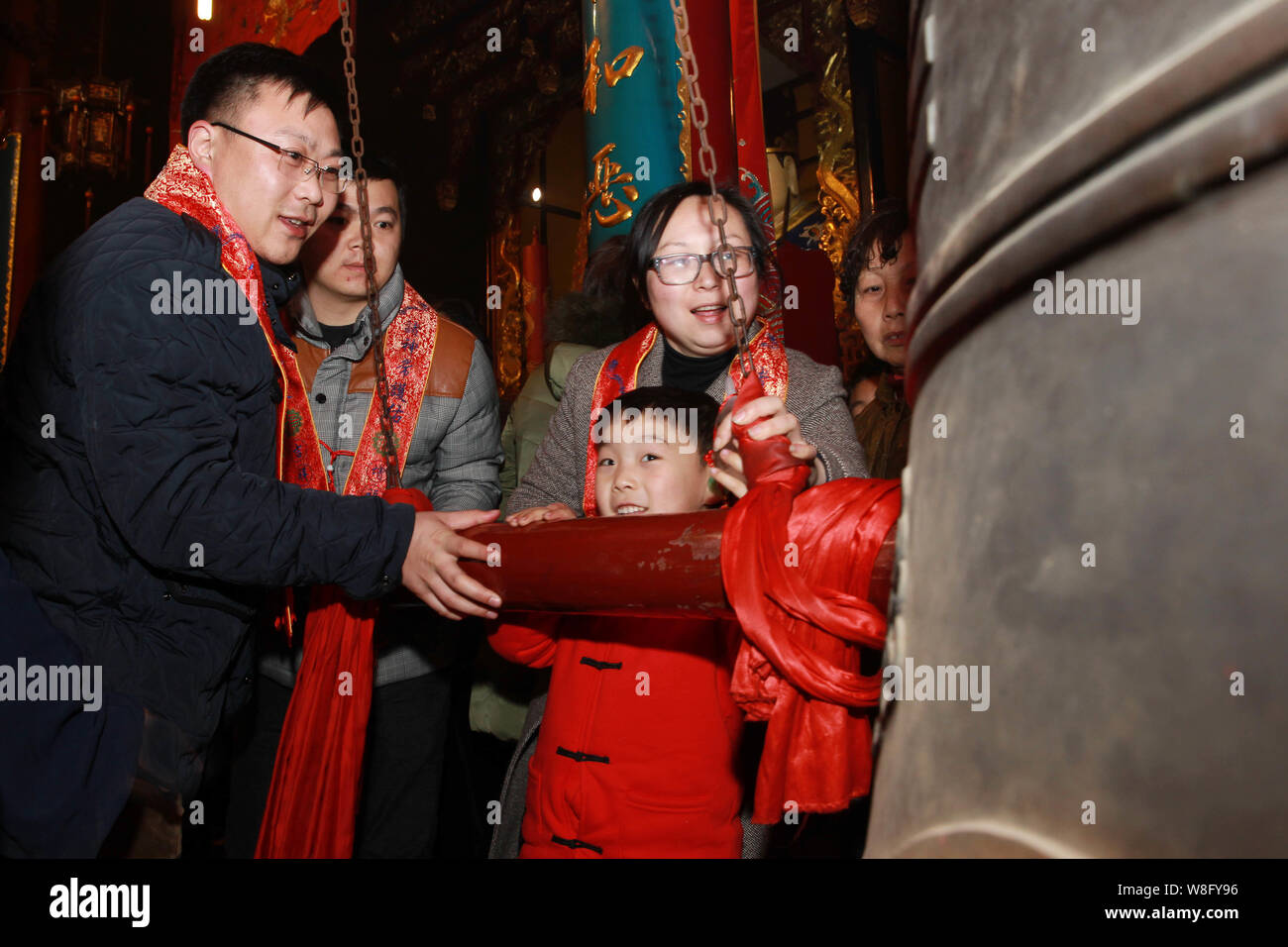 Chinese worshippers strike a bell to pray for good fortune and ...