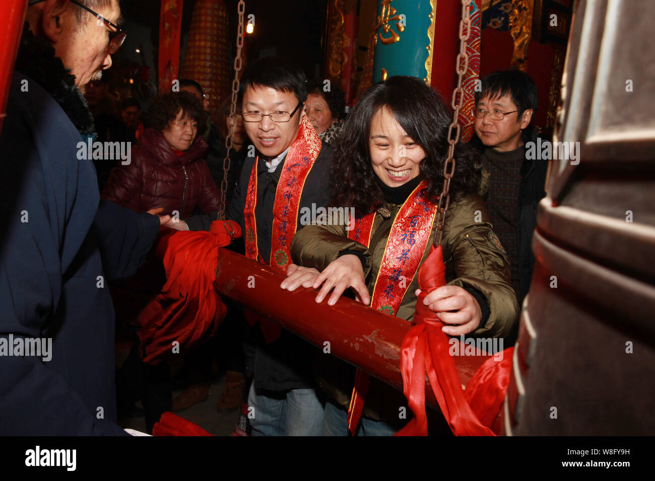 Chinese worshippers strike a bell to pray for good fortune and ...