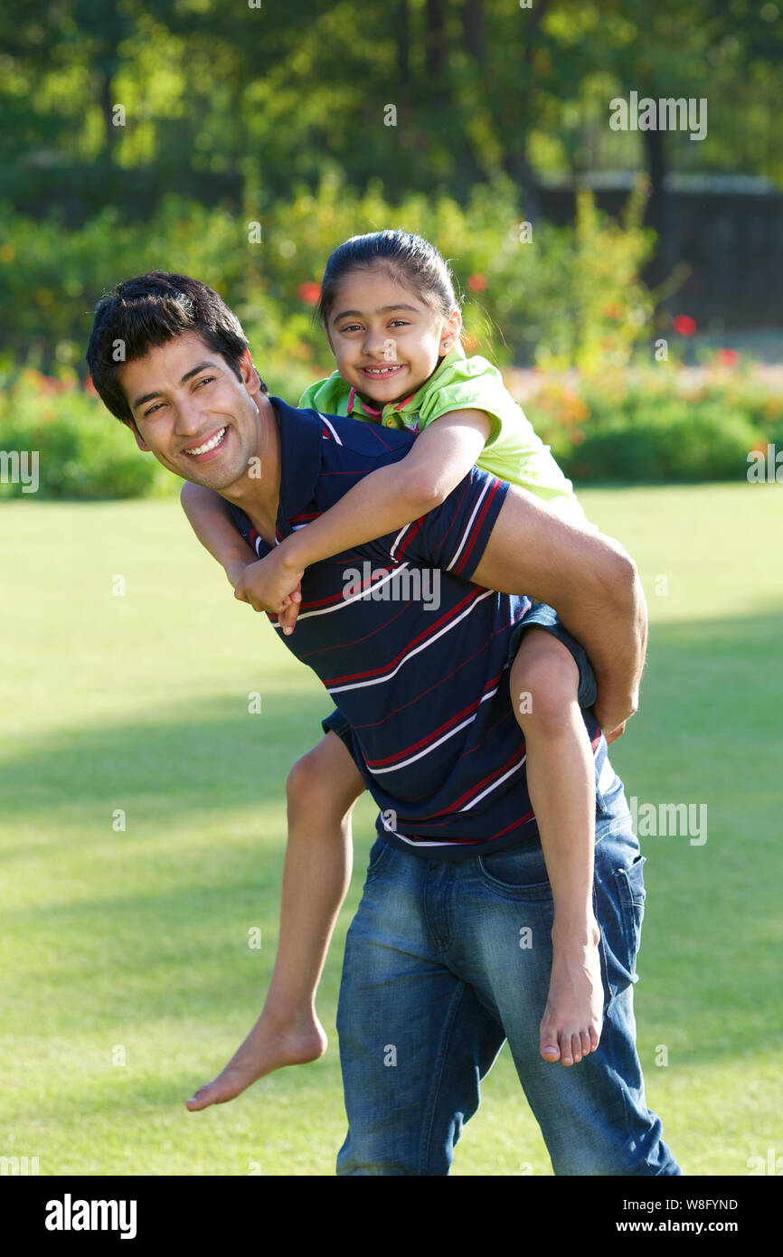 Man giving piggyback to his daughter and smiling Stock Photo - Alamy