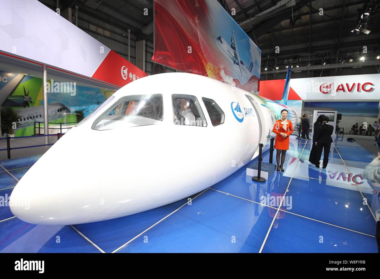 --FILE--A Chinese employee stands next to a model of an MA700 aircraft ...