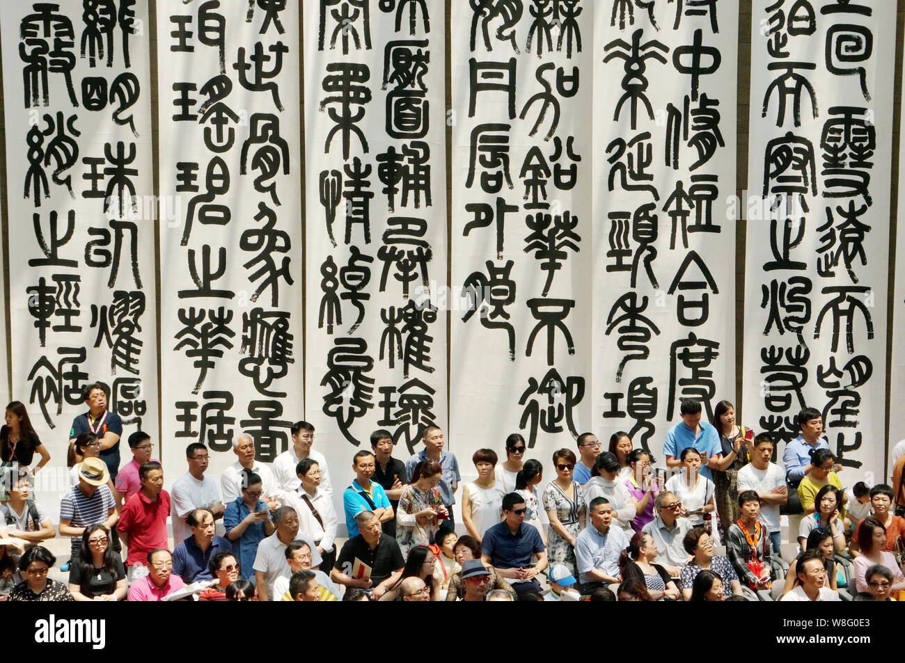 Visitor stand in front of scrolls of calligraphy in an ancient Chinese ...