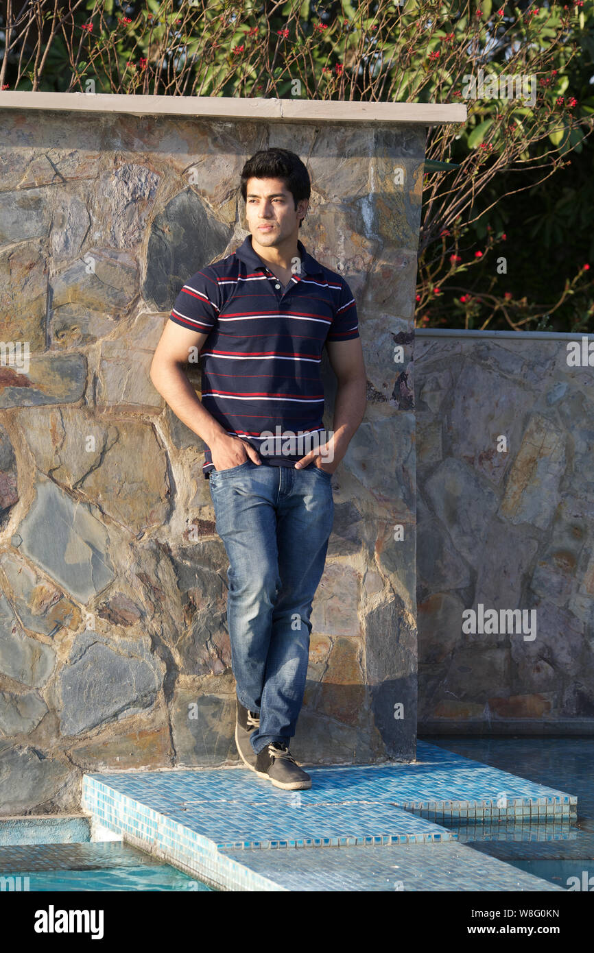 Young man leaning against a stonewall Stock Photo - Alamy