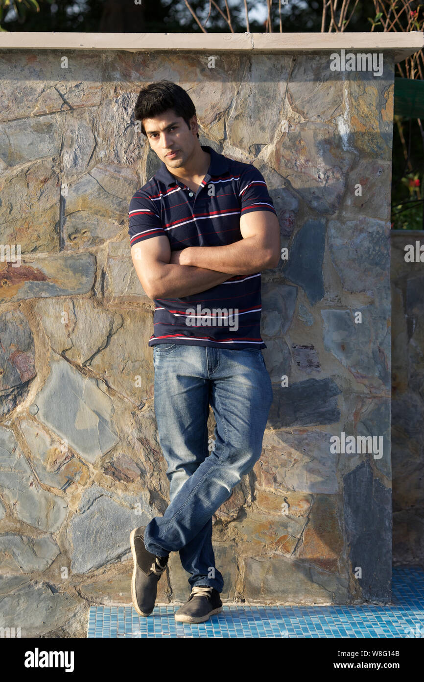 Young man leaning against a stonewall Stock Photo - Alamy