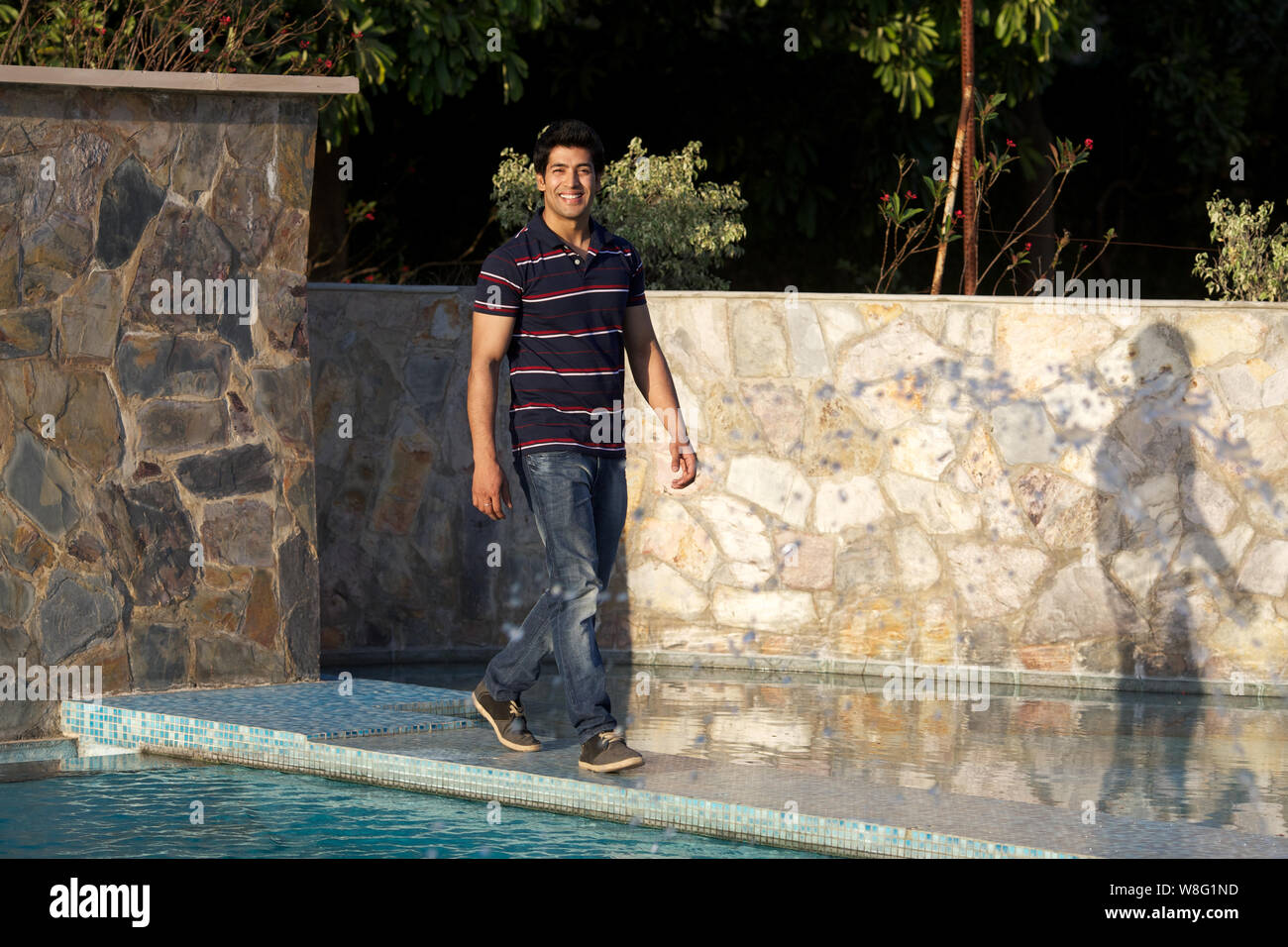 Young man walking at a swimming pool Stock Photo - Alamy