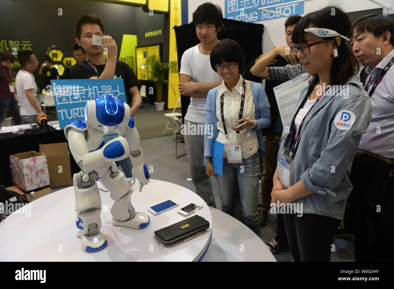 A Chinese visitor, right, uses her brain wave to control a humanoid ...