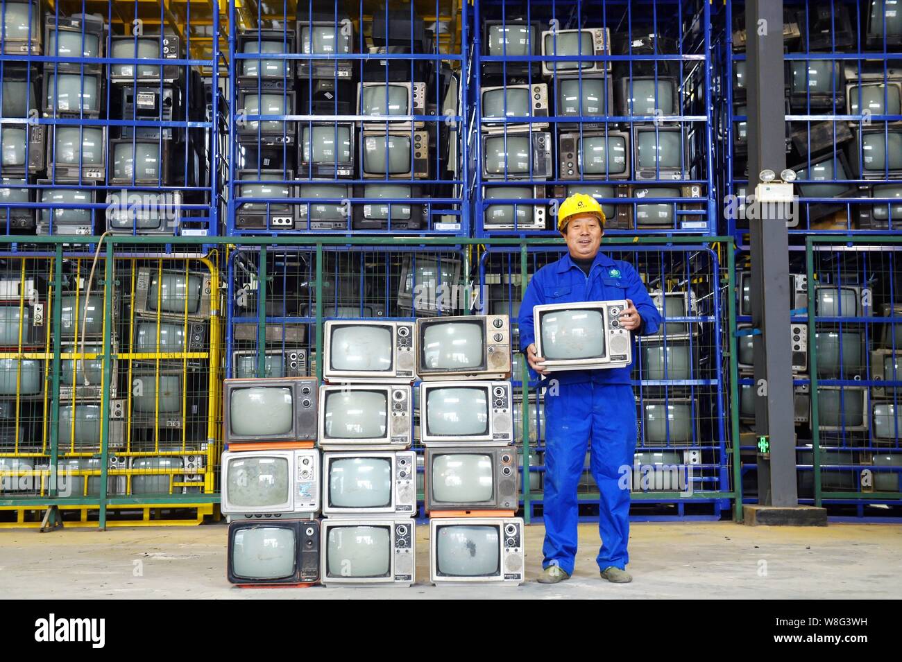 A Chinese worker poses in front of piles of discarded CRT TV sets to be ...