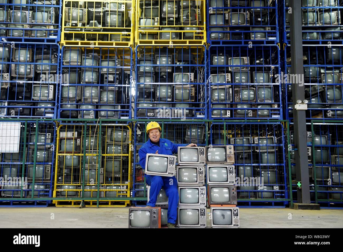 A Chinese worker poses in front of piles of discarded CRT TV sets to be ...