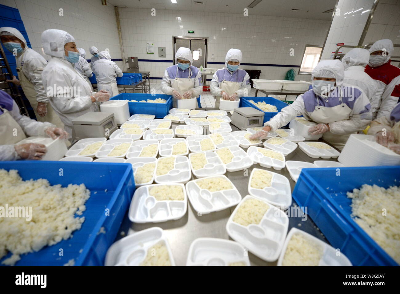 Chinese workers fill lunch boxes with cooked rice on the production ...