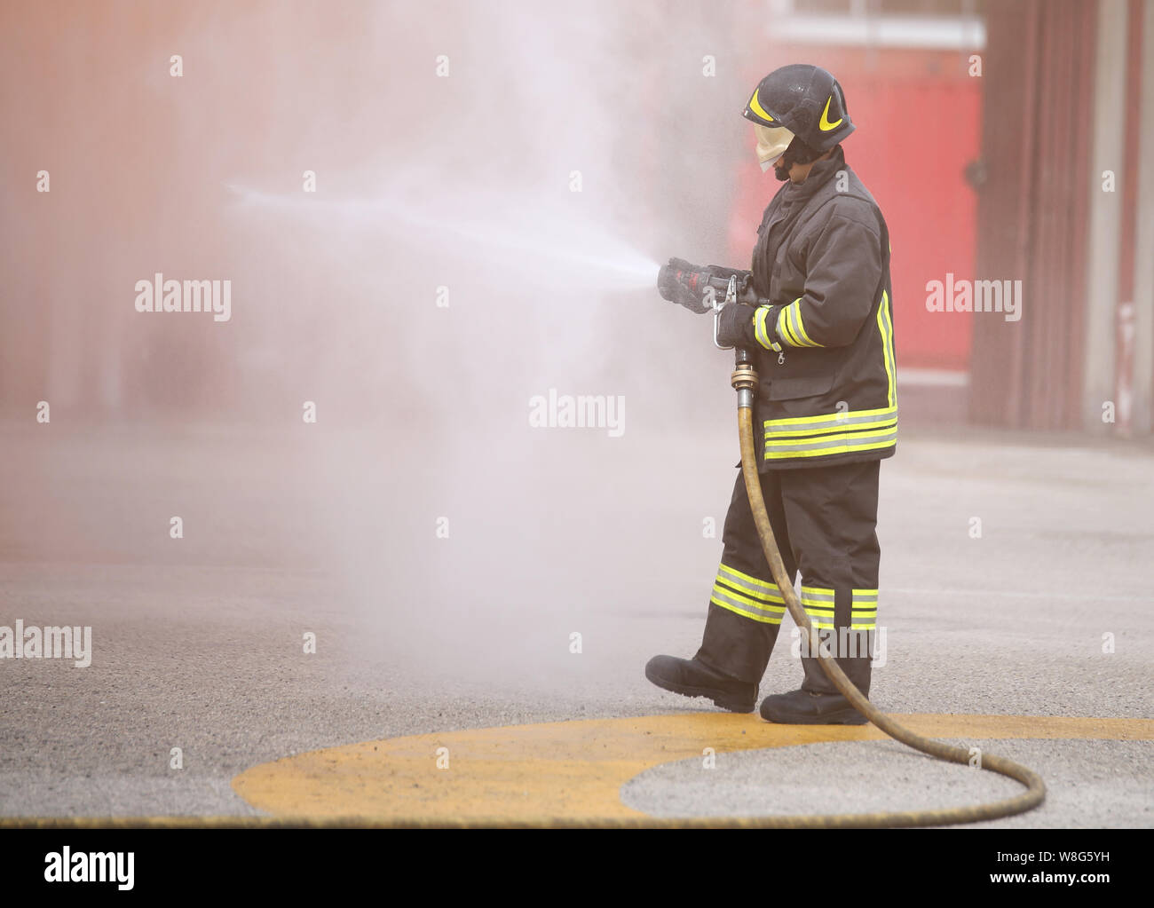 fireman in action with foam during a fire Stock Photo - Alamy