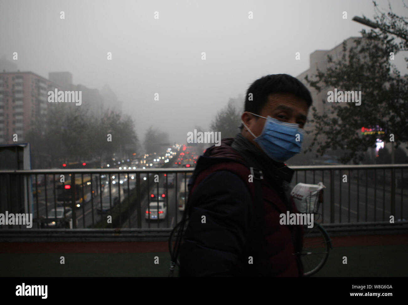 A pedestrian wearing a face mask walks across a footbridge in heavy ...