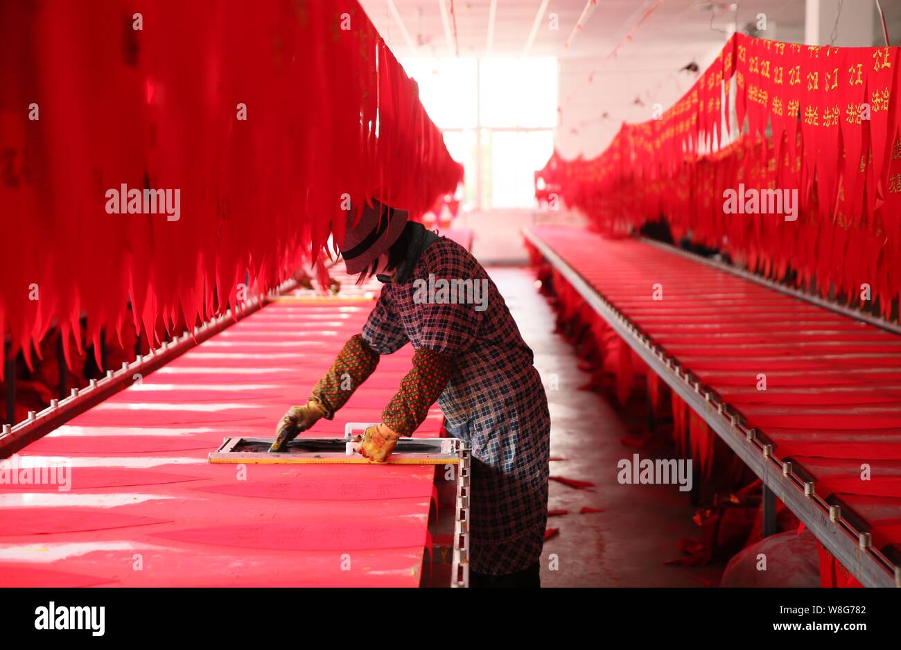 A Chinese worker imprints Chinese characters on fabrics used to make ...