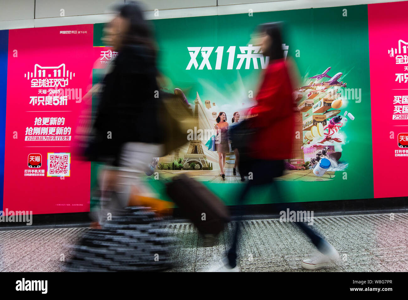 Pedestrians walk past an advertisement for the Tmall 11.11 online shopping festival on the ...