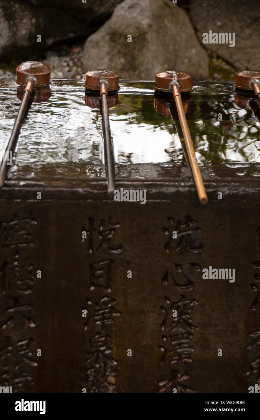 Copper ladles at a stone water basin purification fountain with carved ...