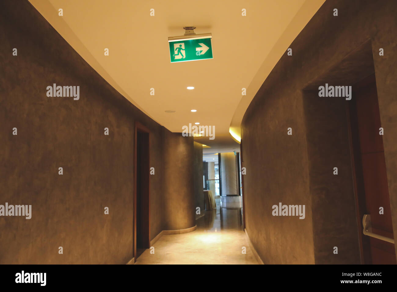 Emergency Exit sign or symbol in empty hotel or office corridor. Green ...