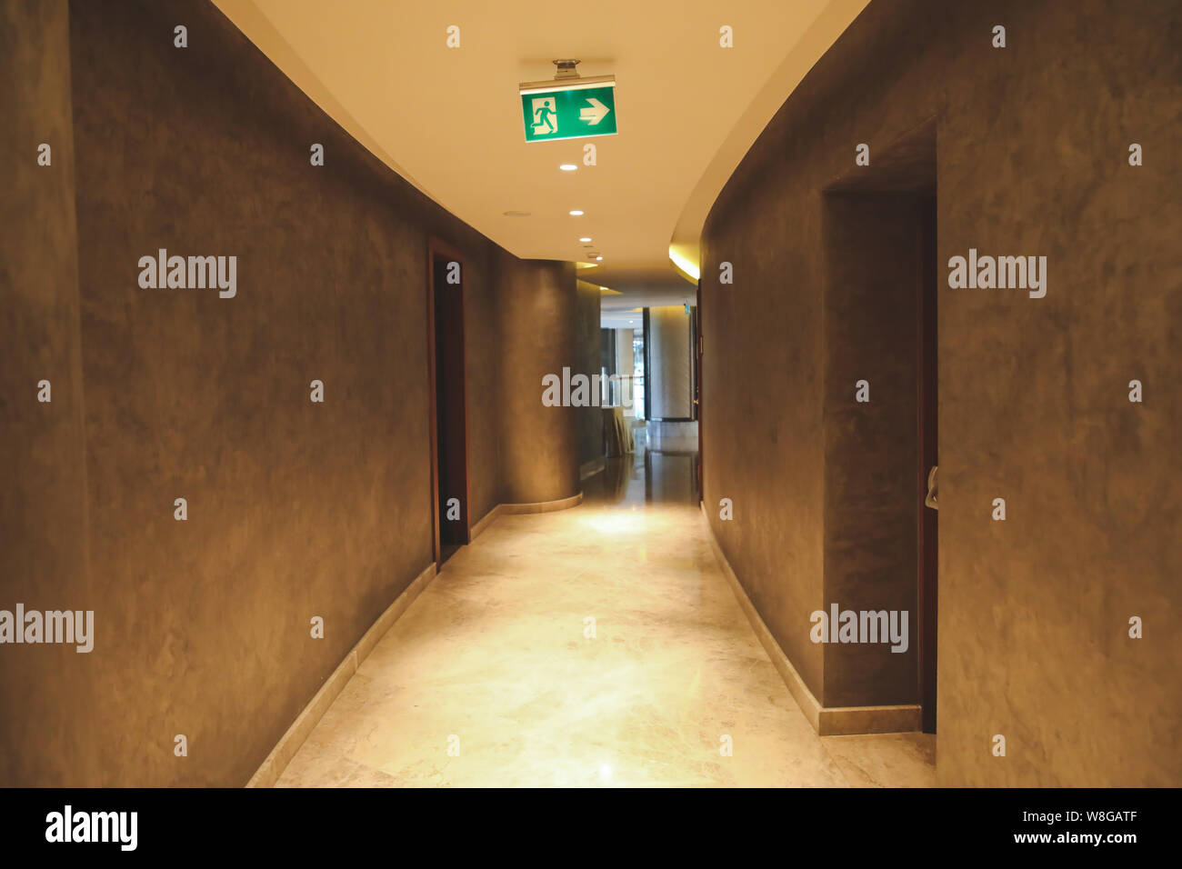 Emergency Exit sign or symbol in empty hotel or office corridor. Green ...