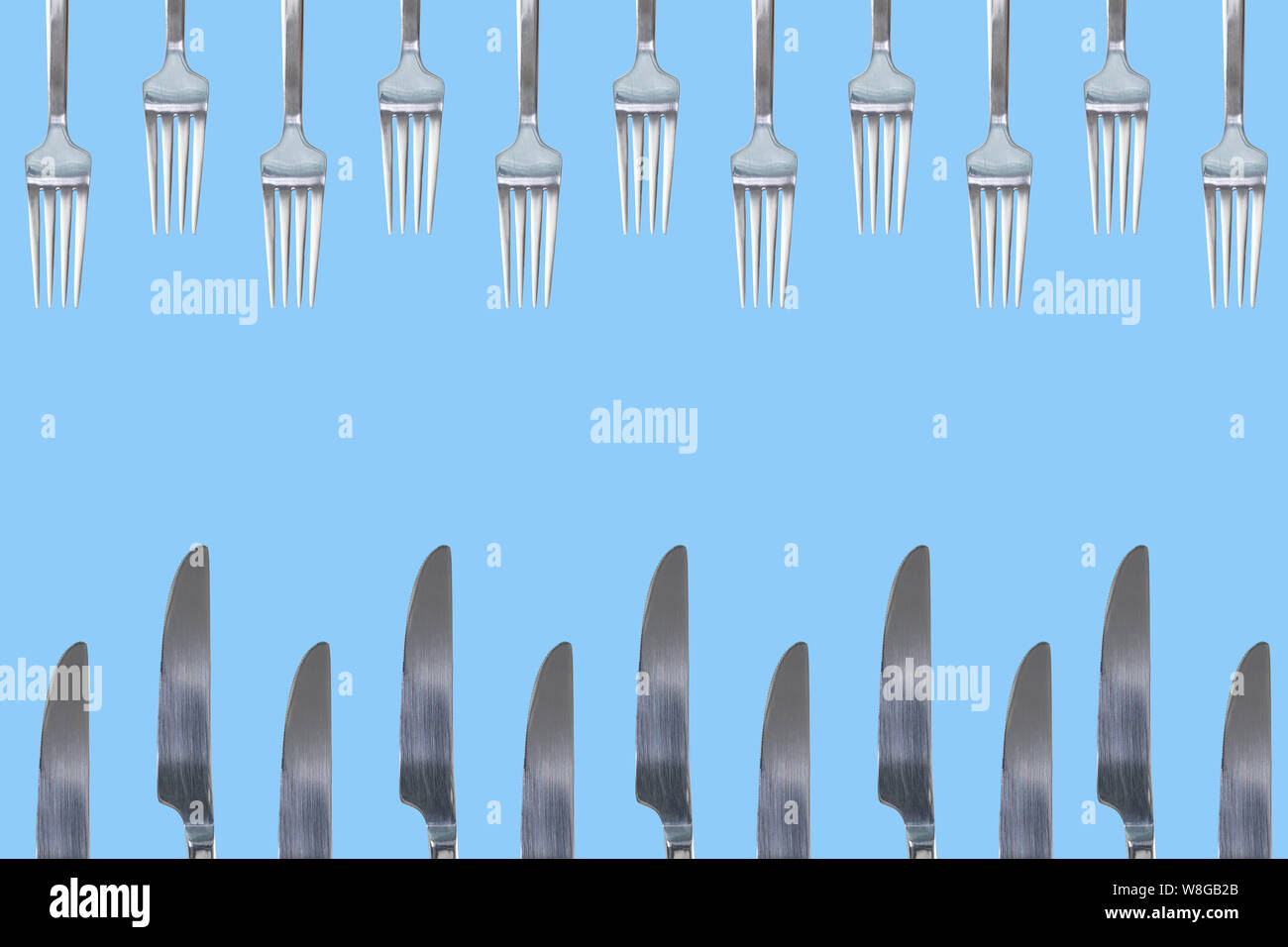 A lot of silver shiny forks and knives. Isolated blue background ...