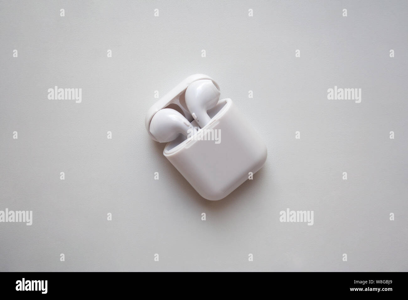 Wireless ear buds in glossy white plastic case isolated on white ...