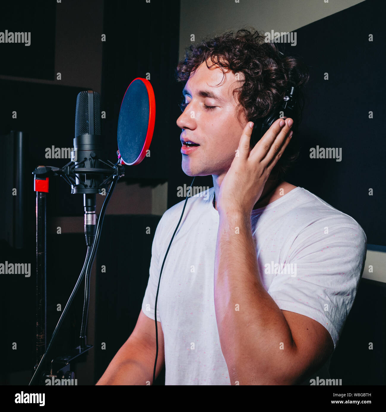 An expressive man sings a song in a microphone in a recording studio ...