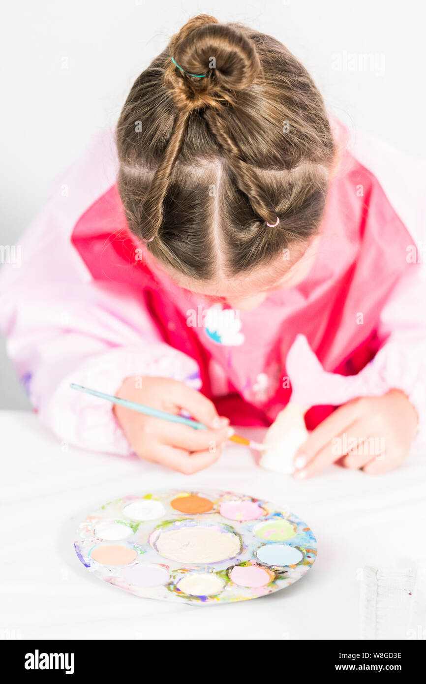 Little girl painting mermaid tails made out of modeling clay with ...