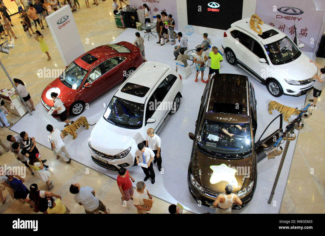 --FILE--Visitors try out or look at Chery cars on display during a ...