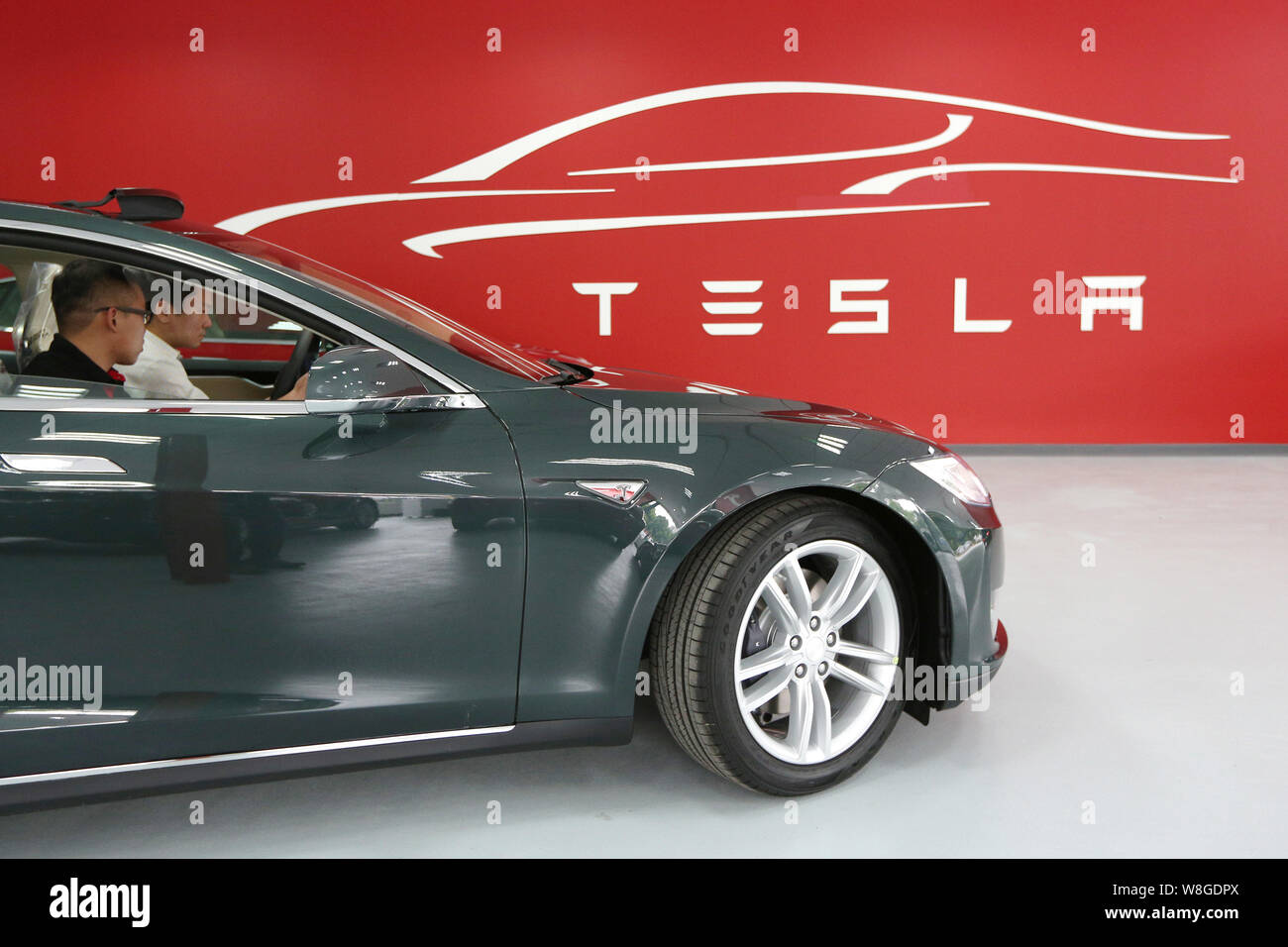 --FILE--Customers try out a Tesla Model S electric car at a dealership ...