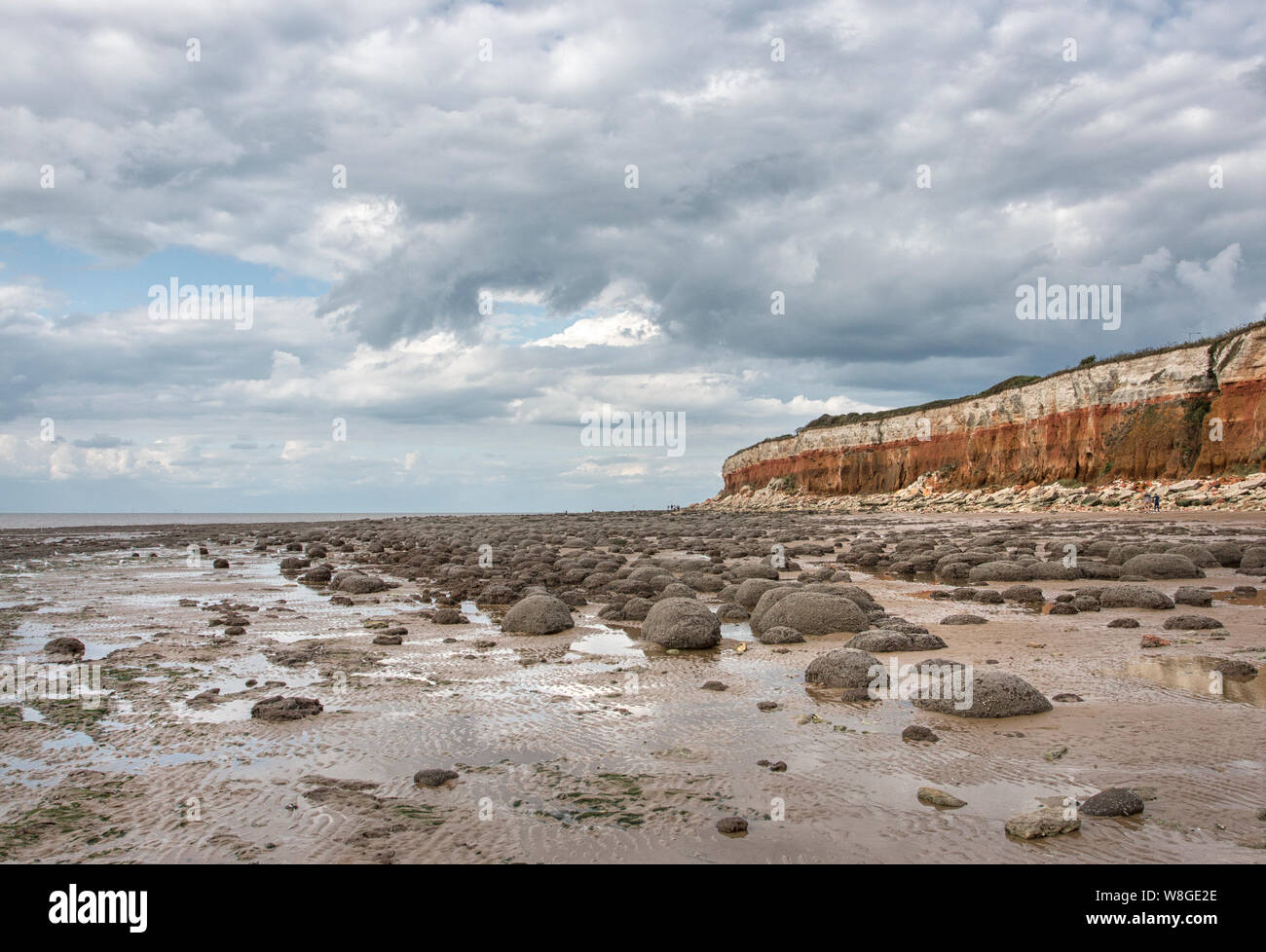 Hunstanton striped cliffs, with rounded boulders on the beach Stock ...