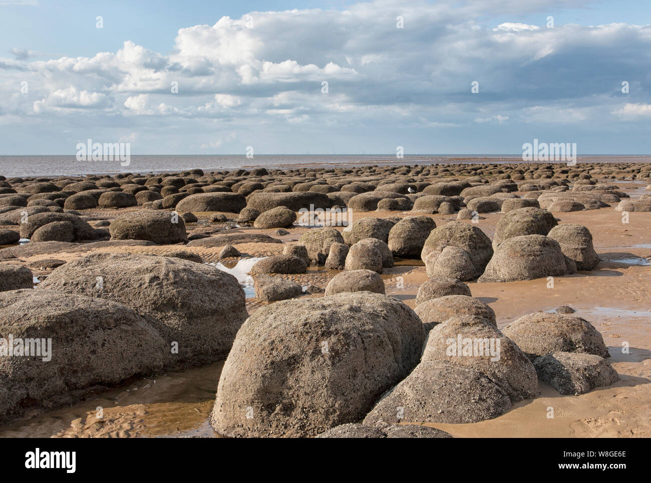 Distinctive large boulders in formation across the sandy beach of ...