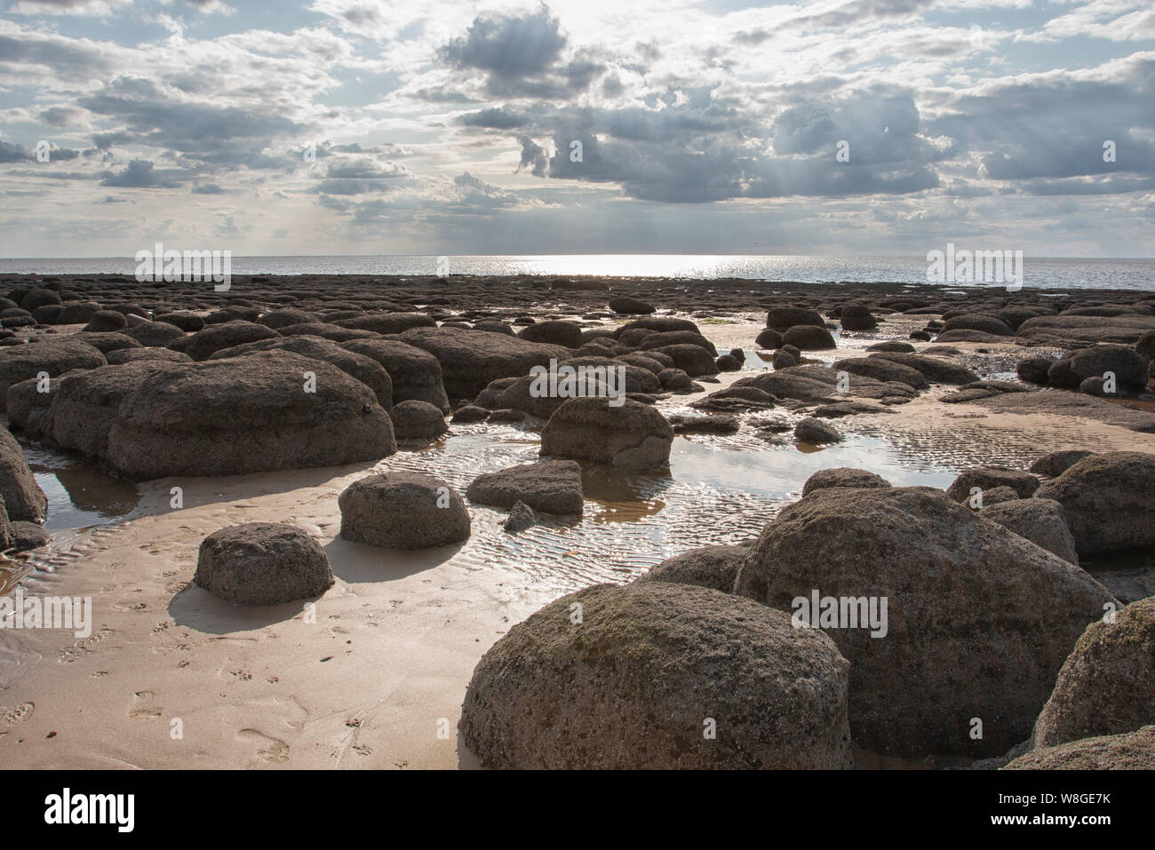 Distinctive large boulders in formation across the sandy beach of ...