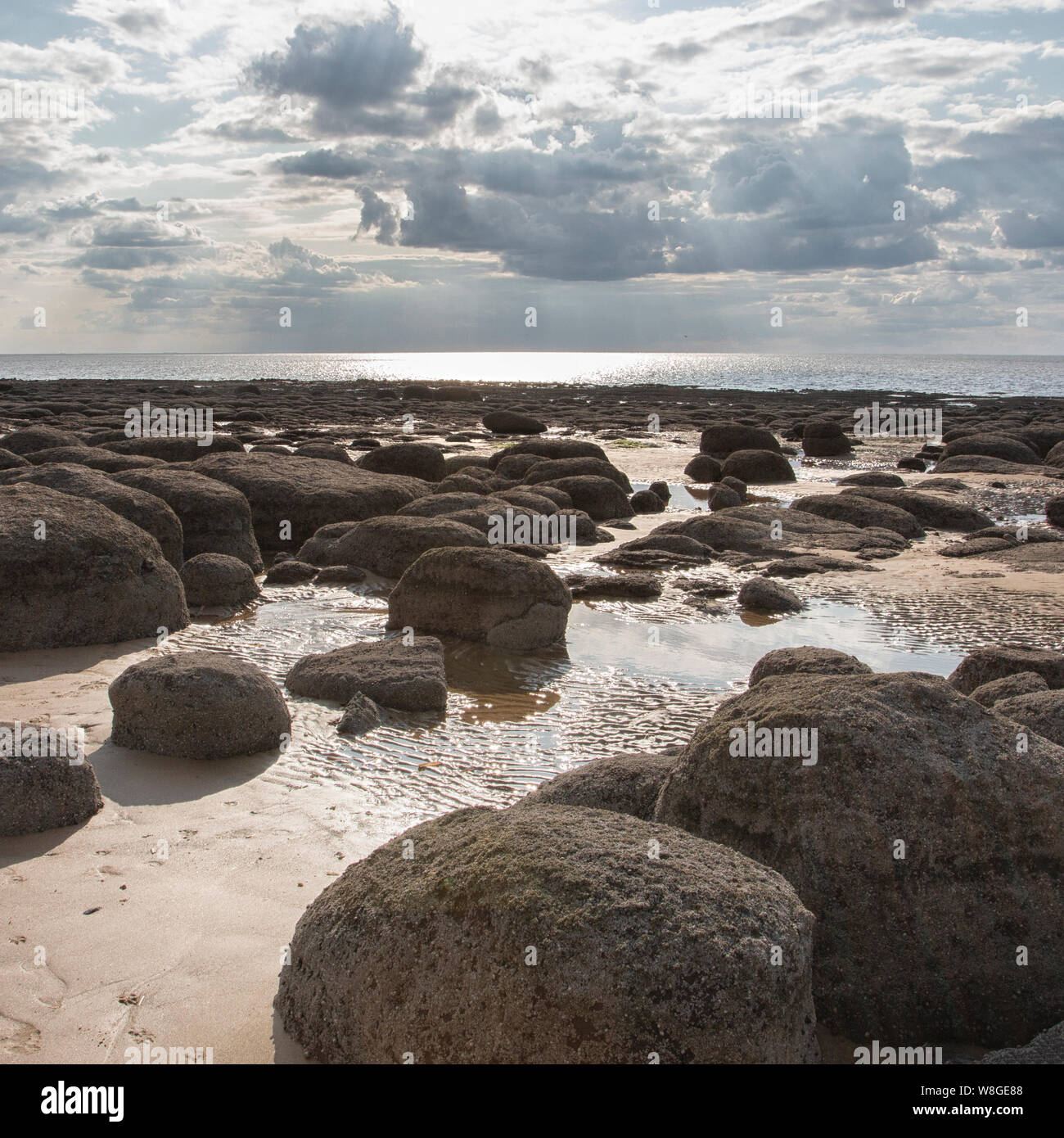 Distinctive large boulders in formation across the sandy beach of ...