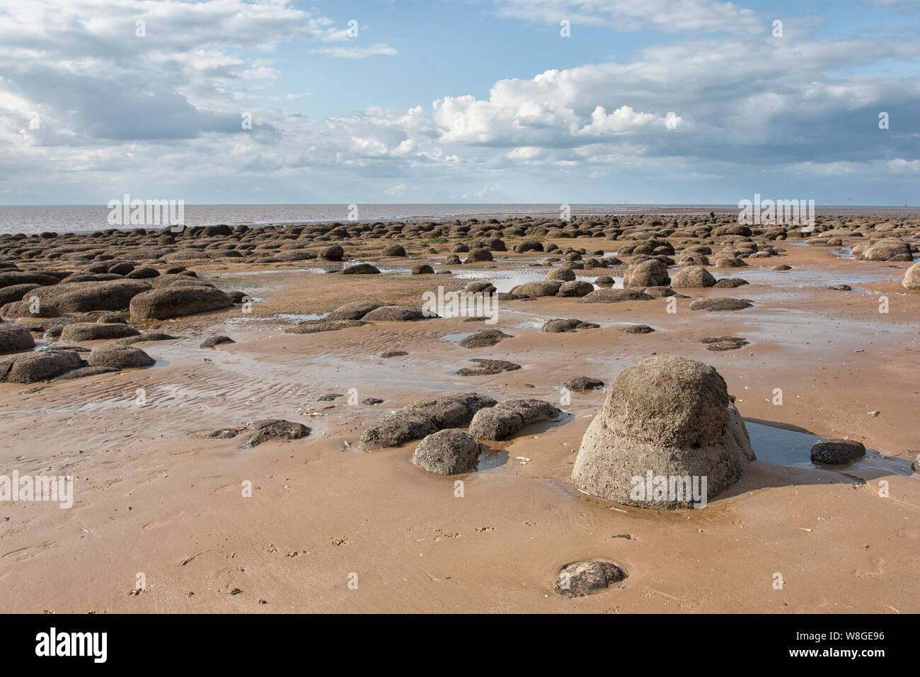 Distinctive large boulders in formation across the sandy beach of ...