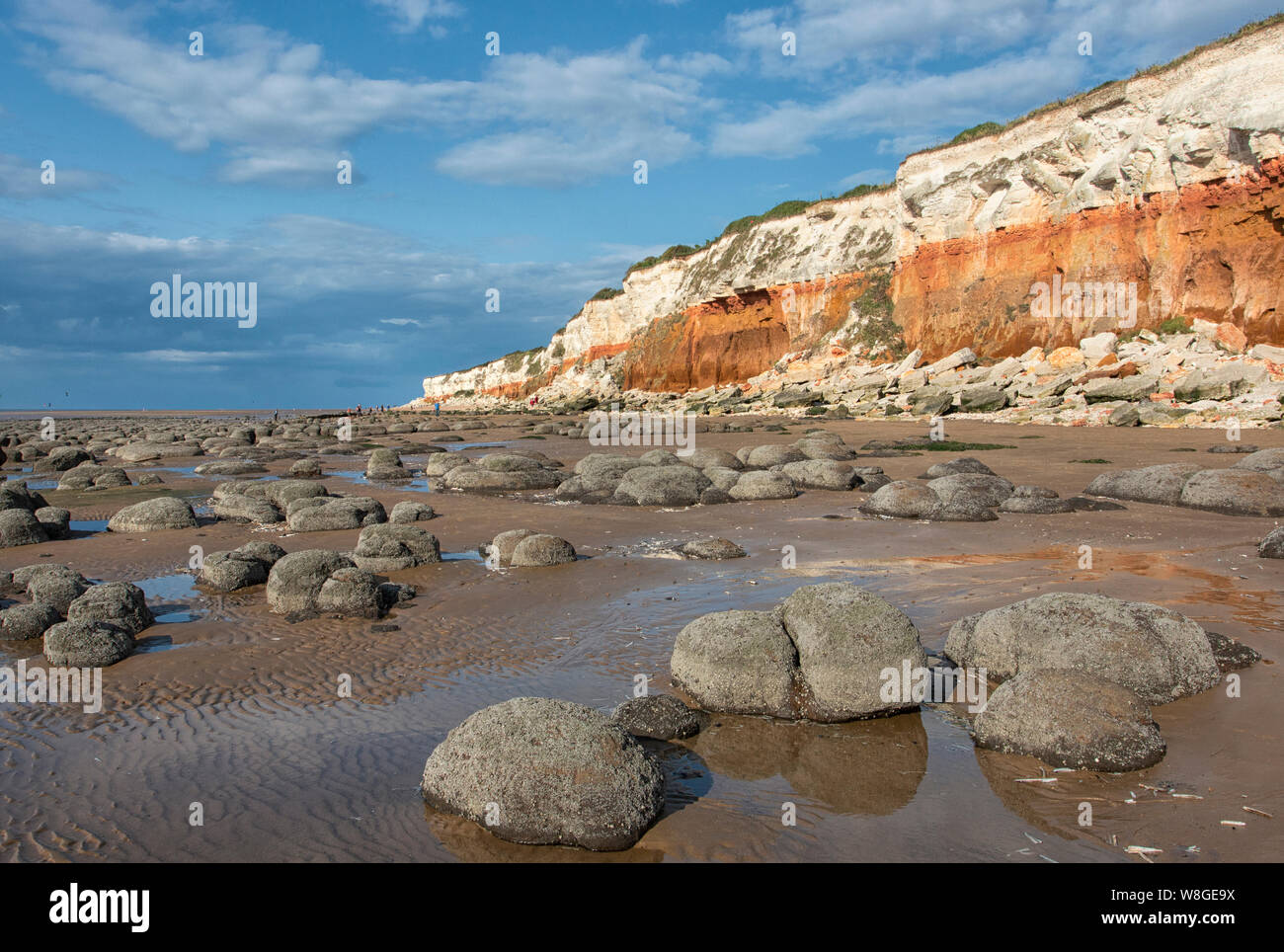 Hunstanton striped cliffs, with rounded boulders on the beach Stock ...