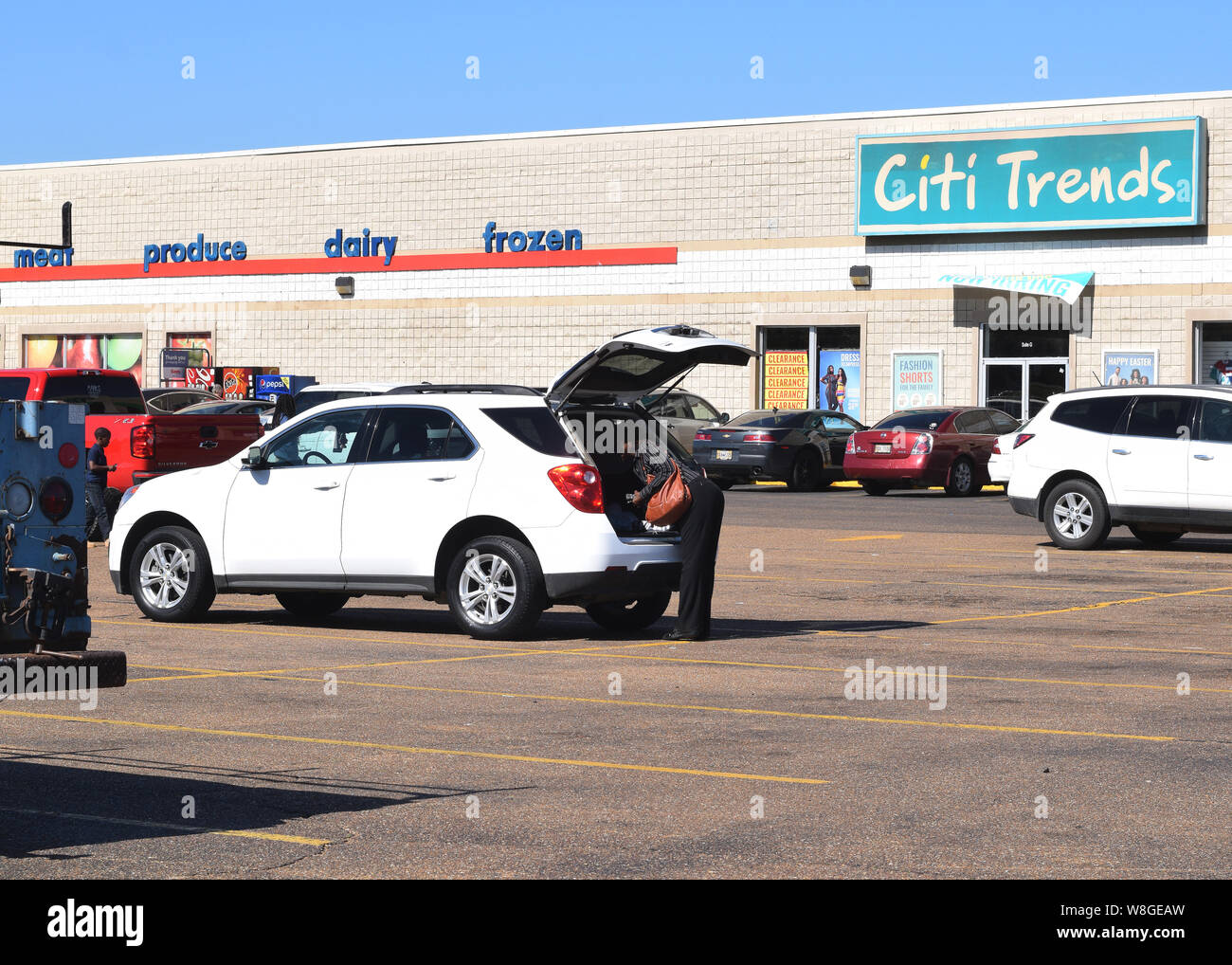 Woman placing packages in trunk of SUV outside of a Citi Trends store ...
