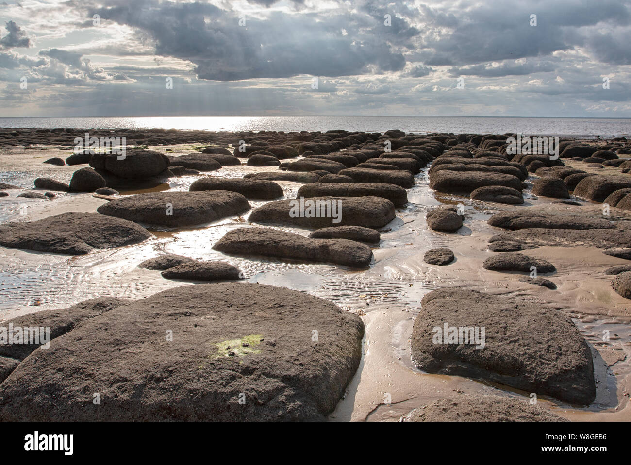 Distinctive large boulders in formation across the sandy beach of ...