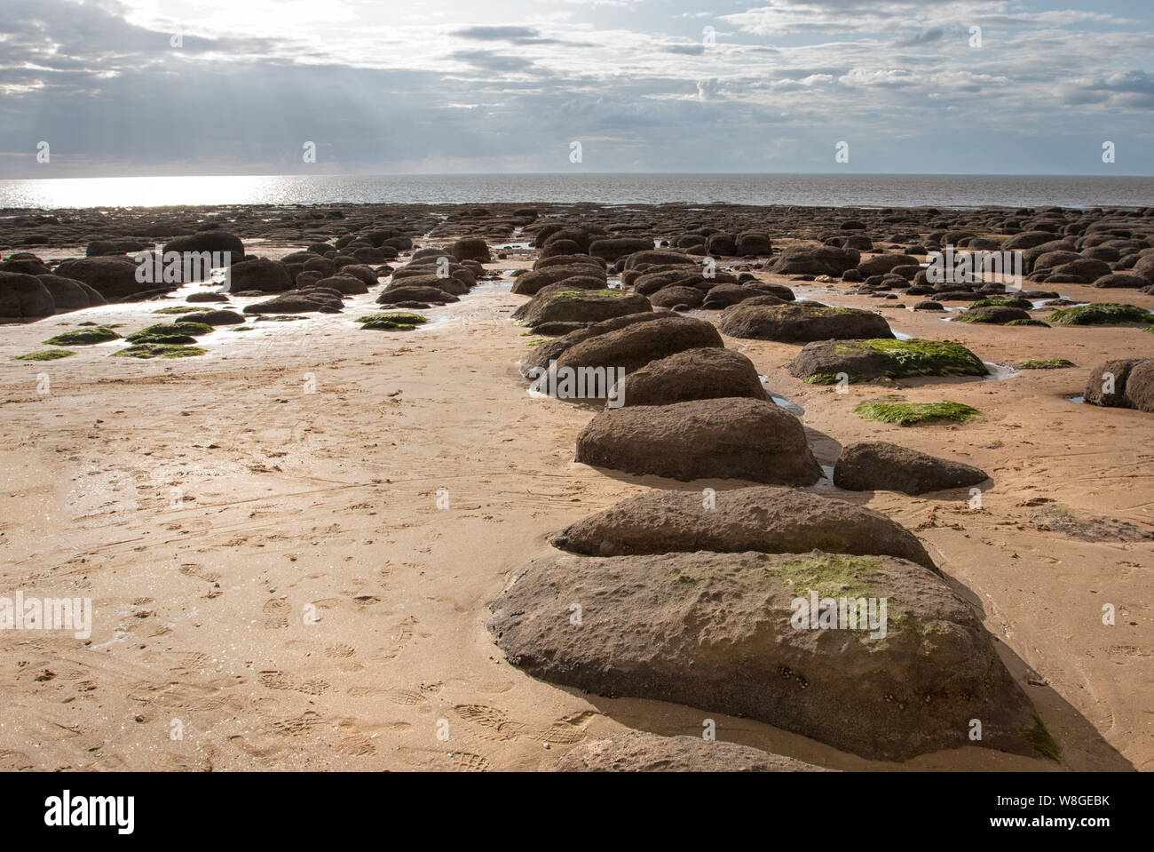 Distinctive large boulders in formation across the sandy beach of ...