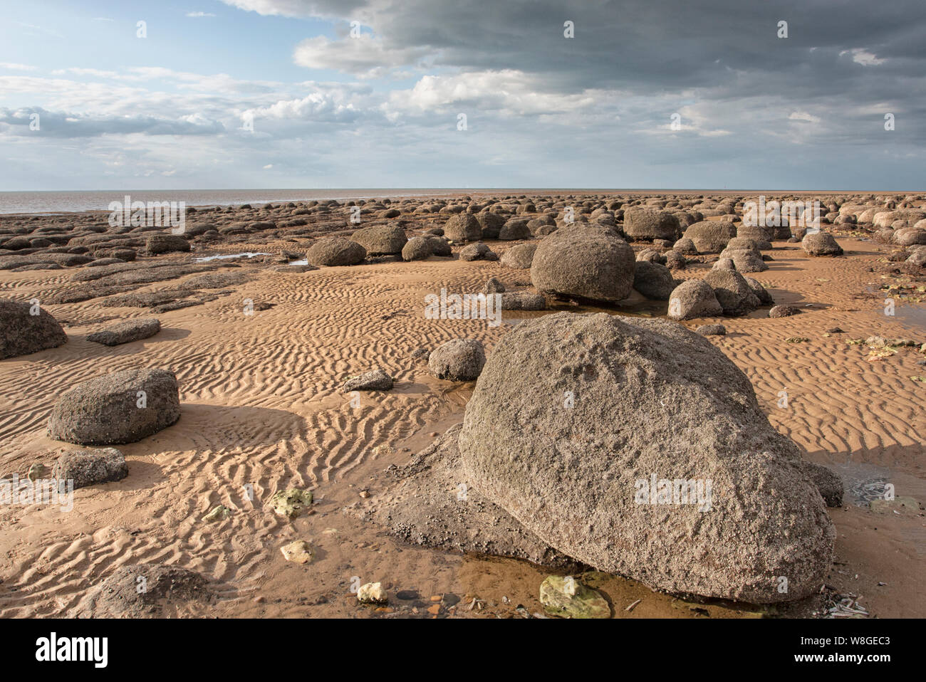Distinctive large boulders in formation across the sandy beach of ...